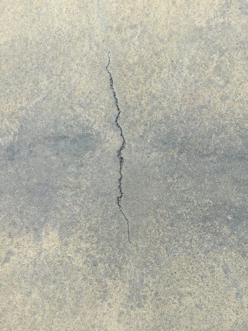 Single crack in center of black asphalt covered with sand | Free Textures